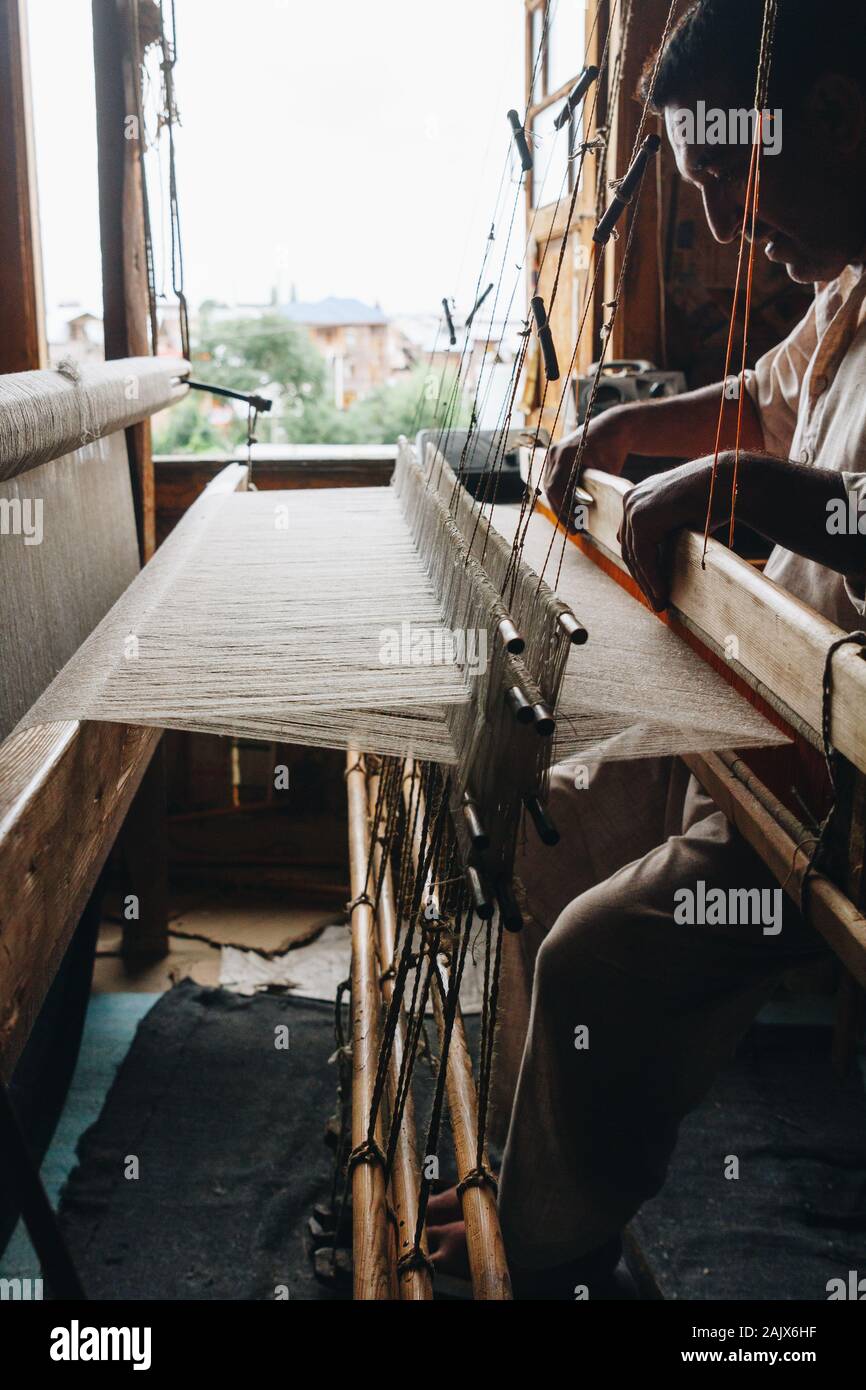 Man weaving a kashmiri pashmina shawl with light source coming from the ...