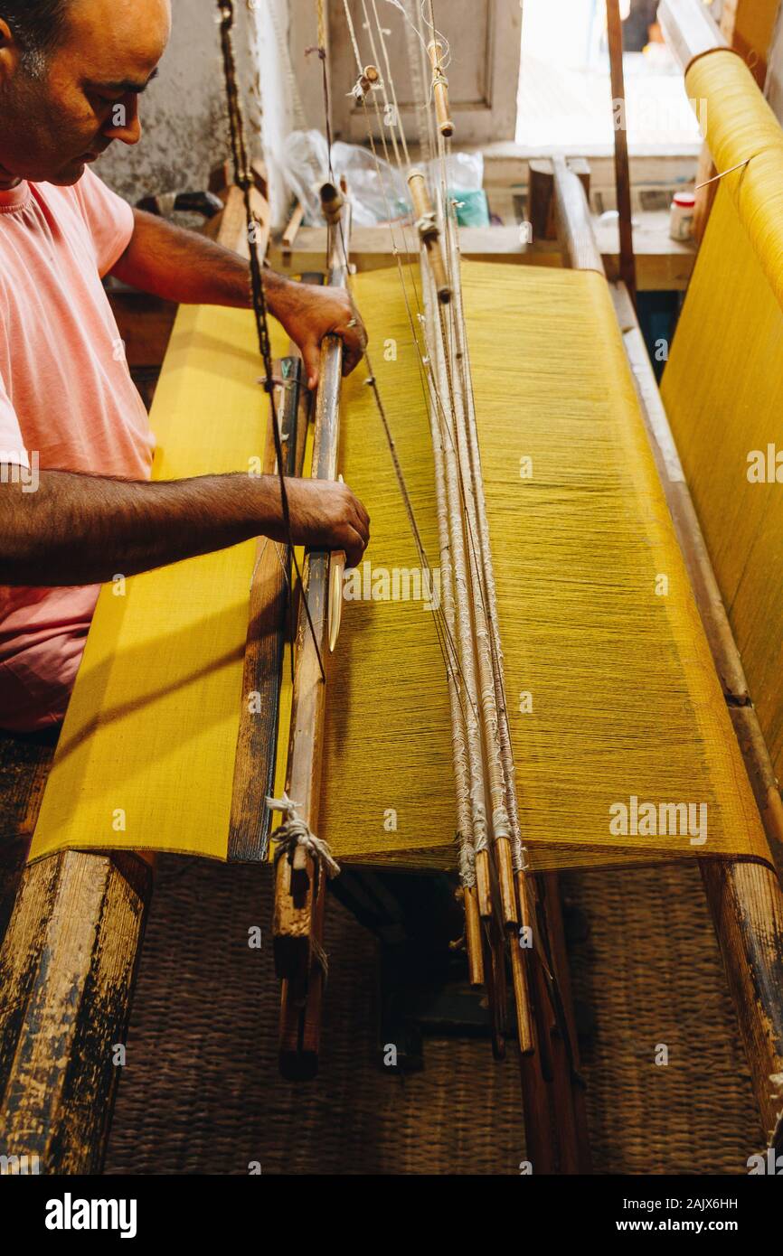 Hand weaving a yellow kashmiri pashmina shawl with light source coming ...