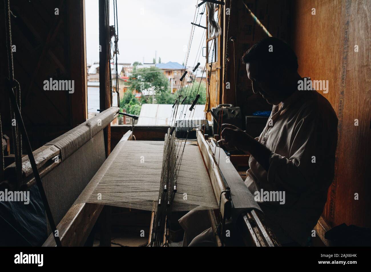Man weaving a kashmiri pashmina shawl with light source coming from the ...