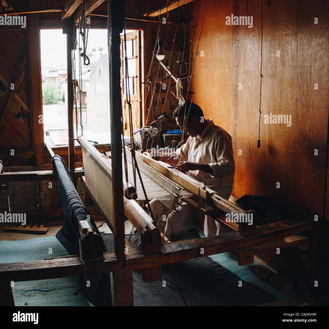 Man weaving a kashmiri pashmina shawl with light source coming from the ...