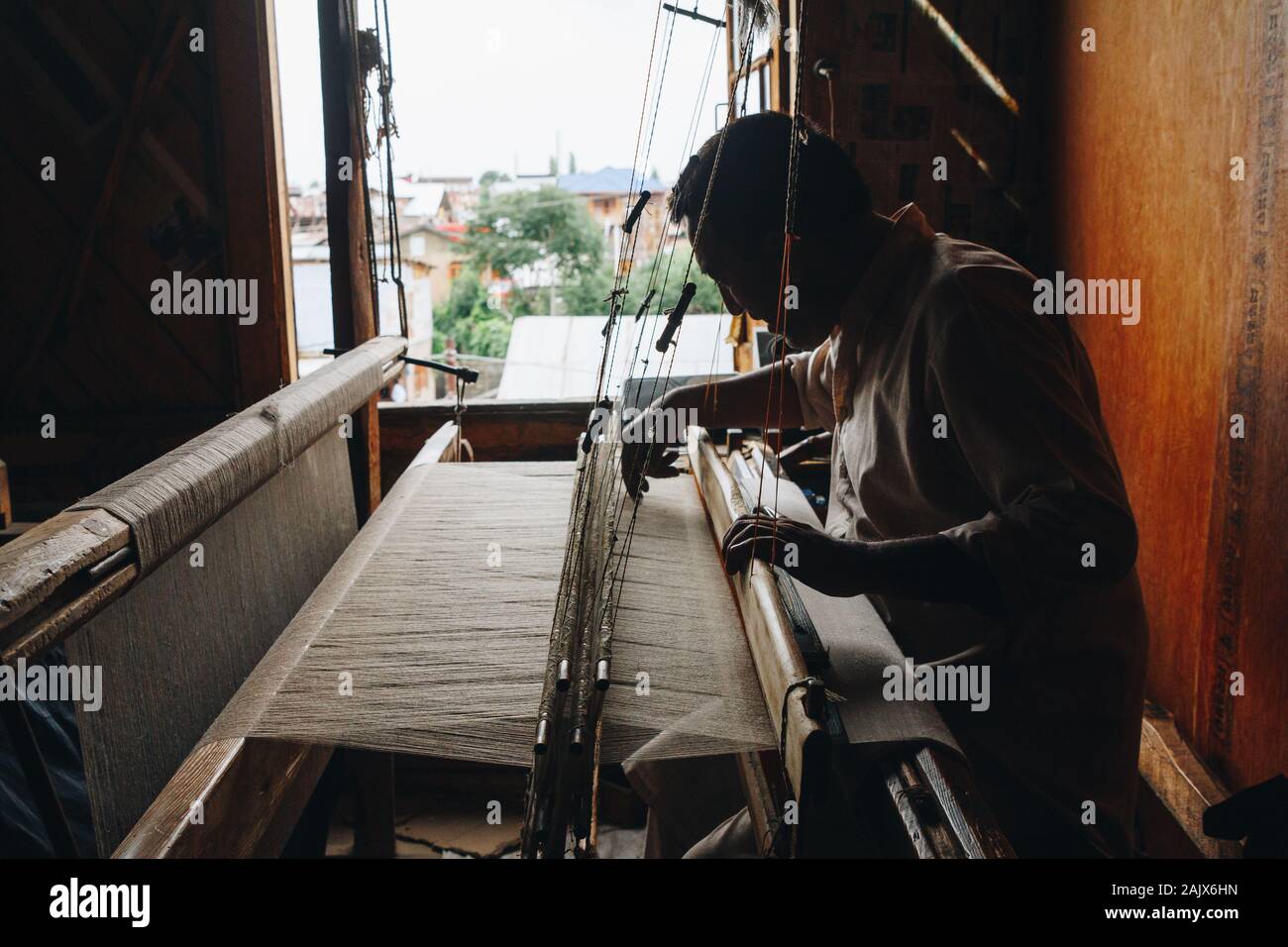 Man weaving a kashmiri pashmina shawl with light source coming from the ...