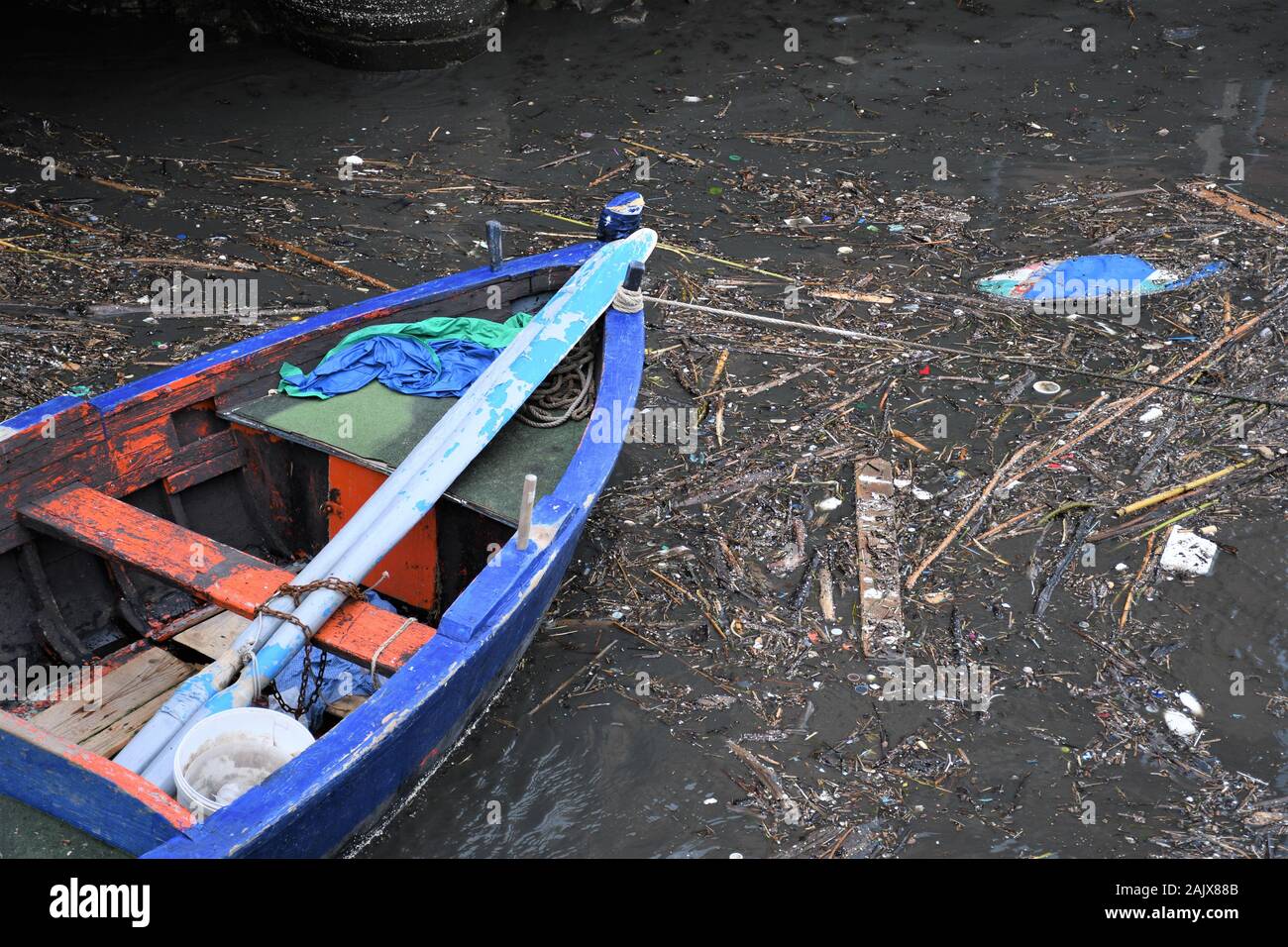 Plastic and microplastic waste floating in the water with wooden boat ...
