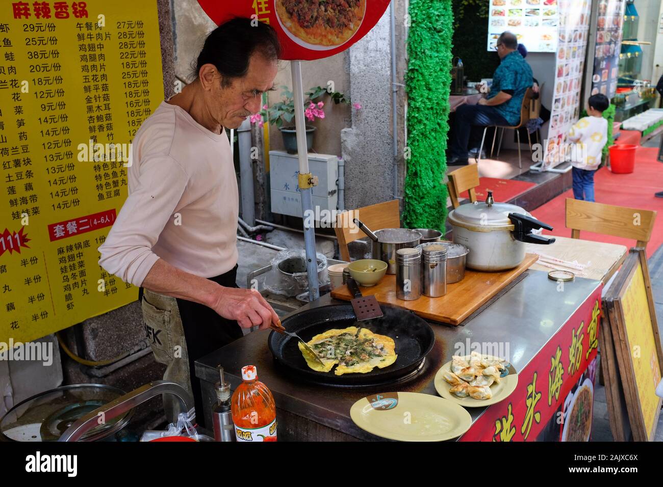 A man cooks food at a street stall on the island of Gulangyu in Xiamen ...