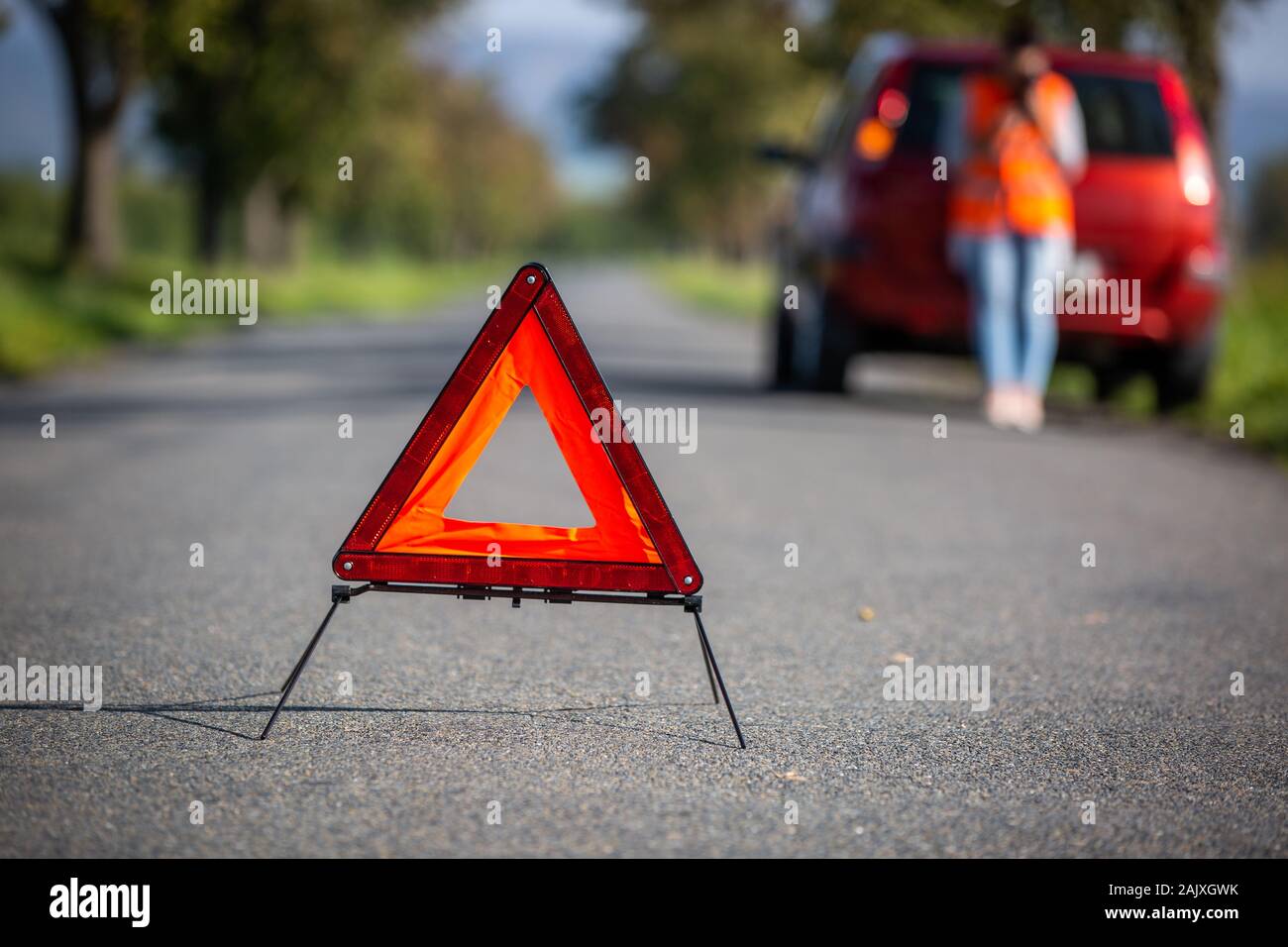 Annoyed young woman in a road distress situation - setting up a warning ...
