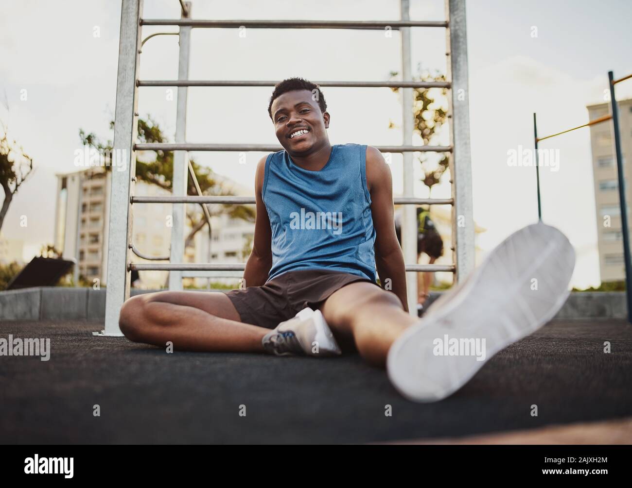 Smiling portrait of a tired sporty young male athlete relaxing after ...