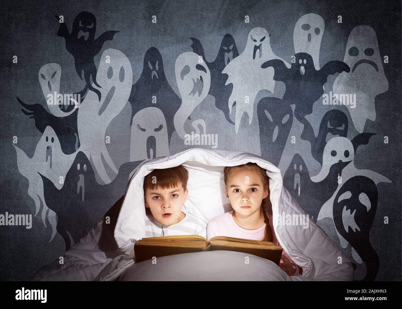 Scared girl and boy reading book in bed Stock Photo - Alamy