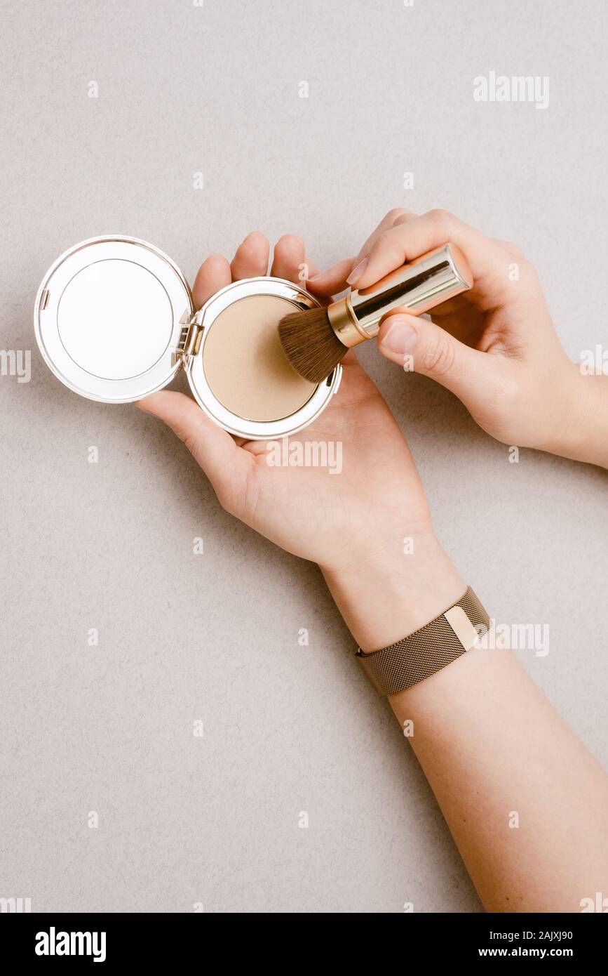 Compact powder with a mirror in the hands of a young girl, close ...