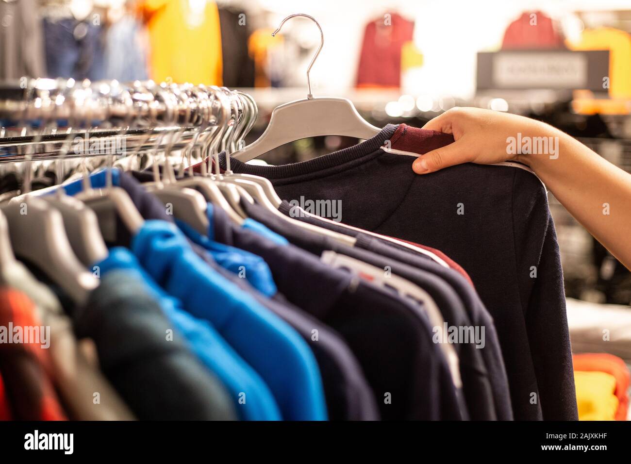 Young woman choosing the clothes in the huge shopping center during big ...