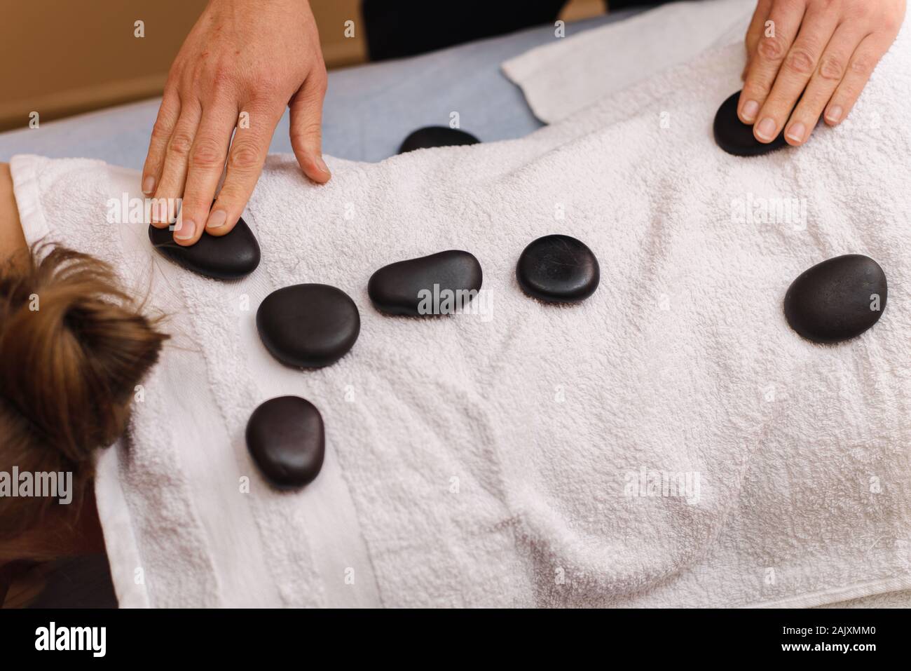 black flat hot spa stones on a towel on a person s back. Warming up and ...