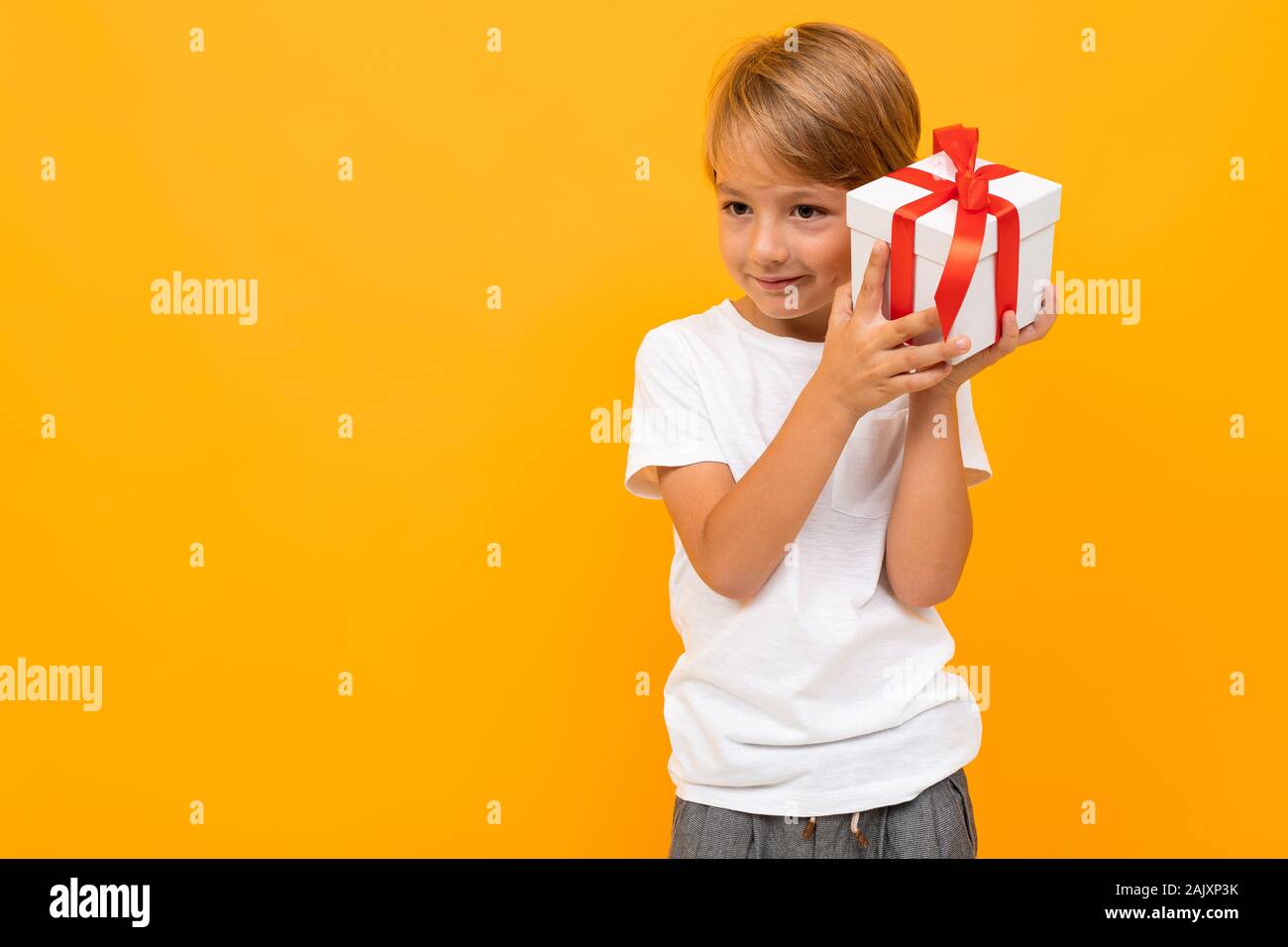 holiday concept. attractive boy with gift box on bright yellow ...