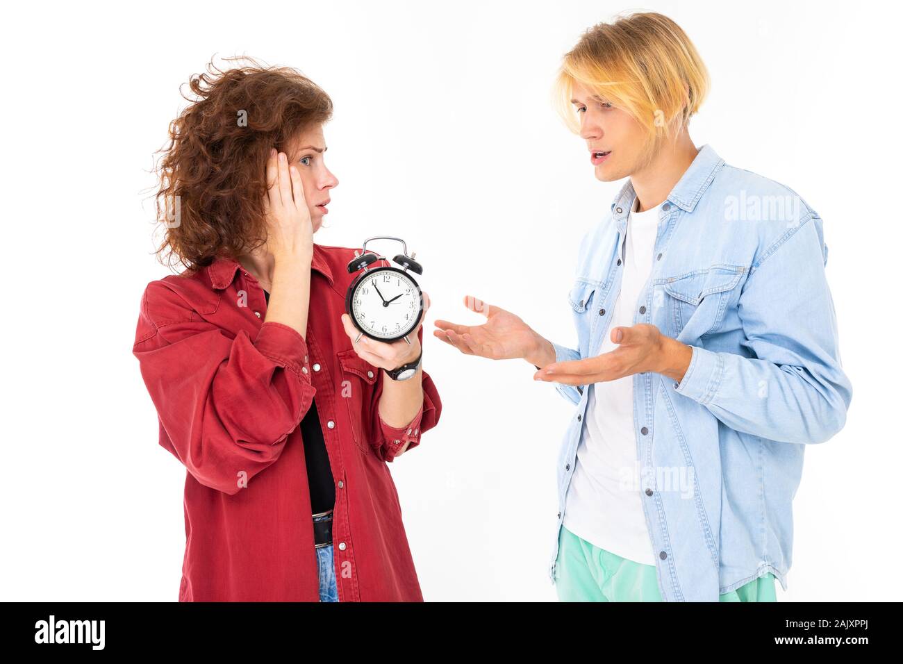 charming girl with an alarm clock stands near her boyfriend, who ...
