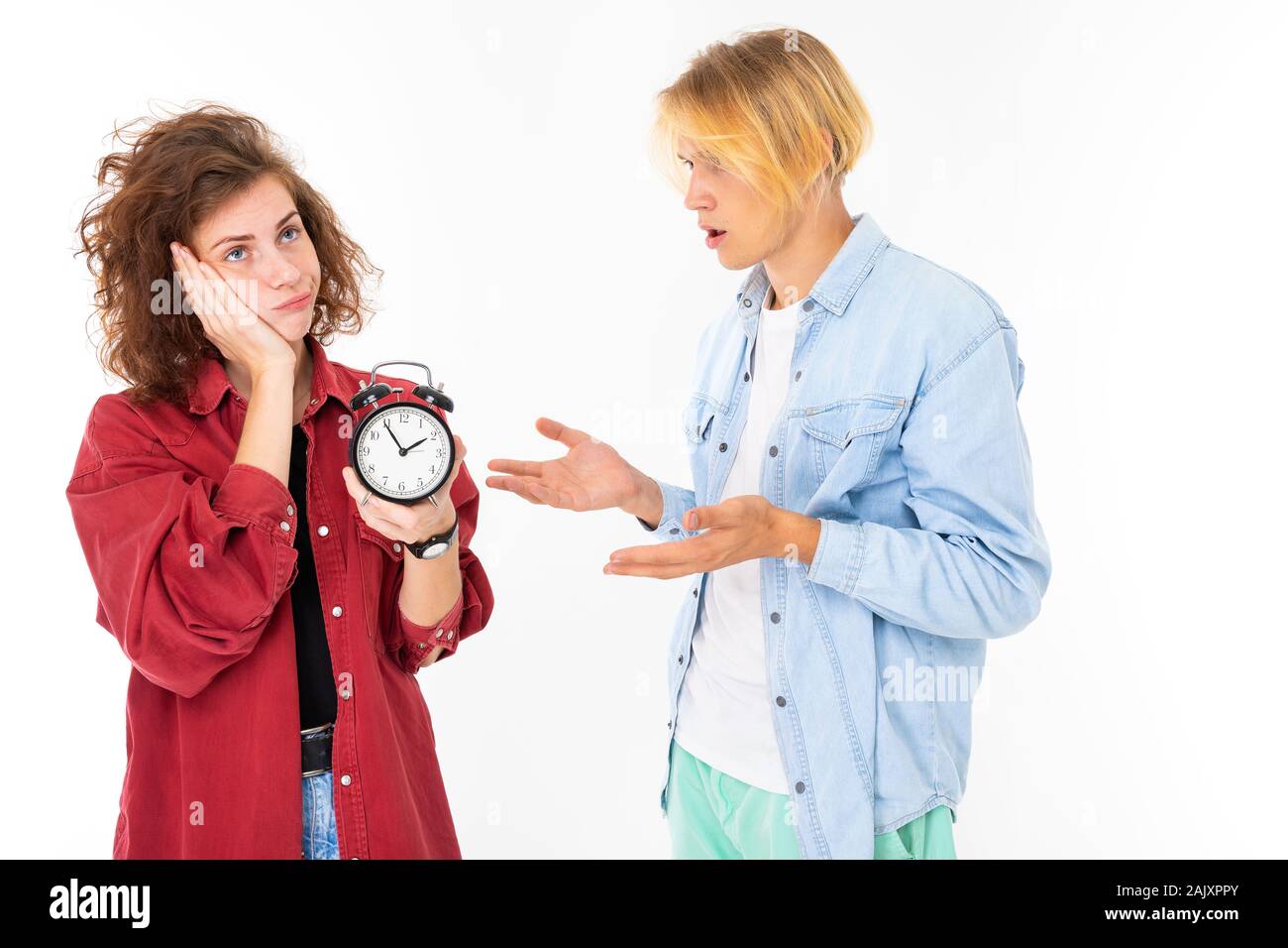 charming girl with an alarm clock stands near her boyfriend, who ...