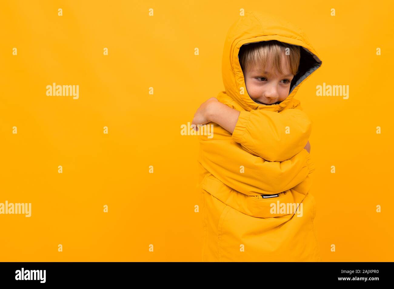 A cute boy in a yellow hoodie hugged himself and was shy Stock Photo ...