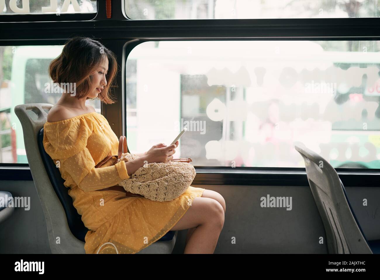 young beautiful asian woman browsing and typing messages in a public ...