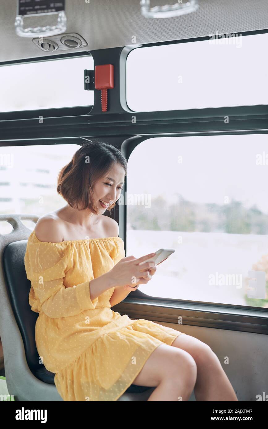 Asian girl using phone on public bus Stock Photo - Alamy