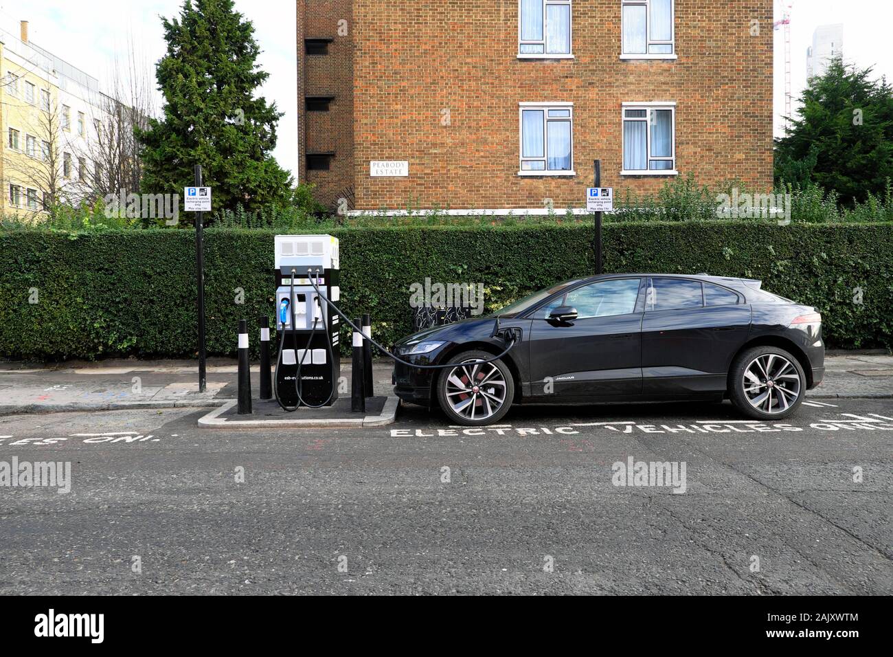 Electric car vehicle charging at power charge point EV station street ...