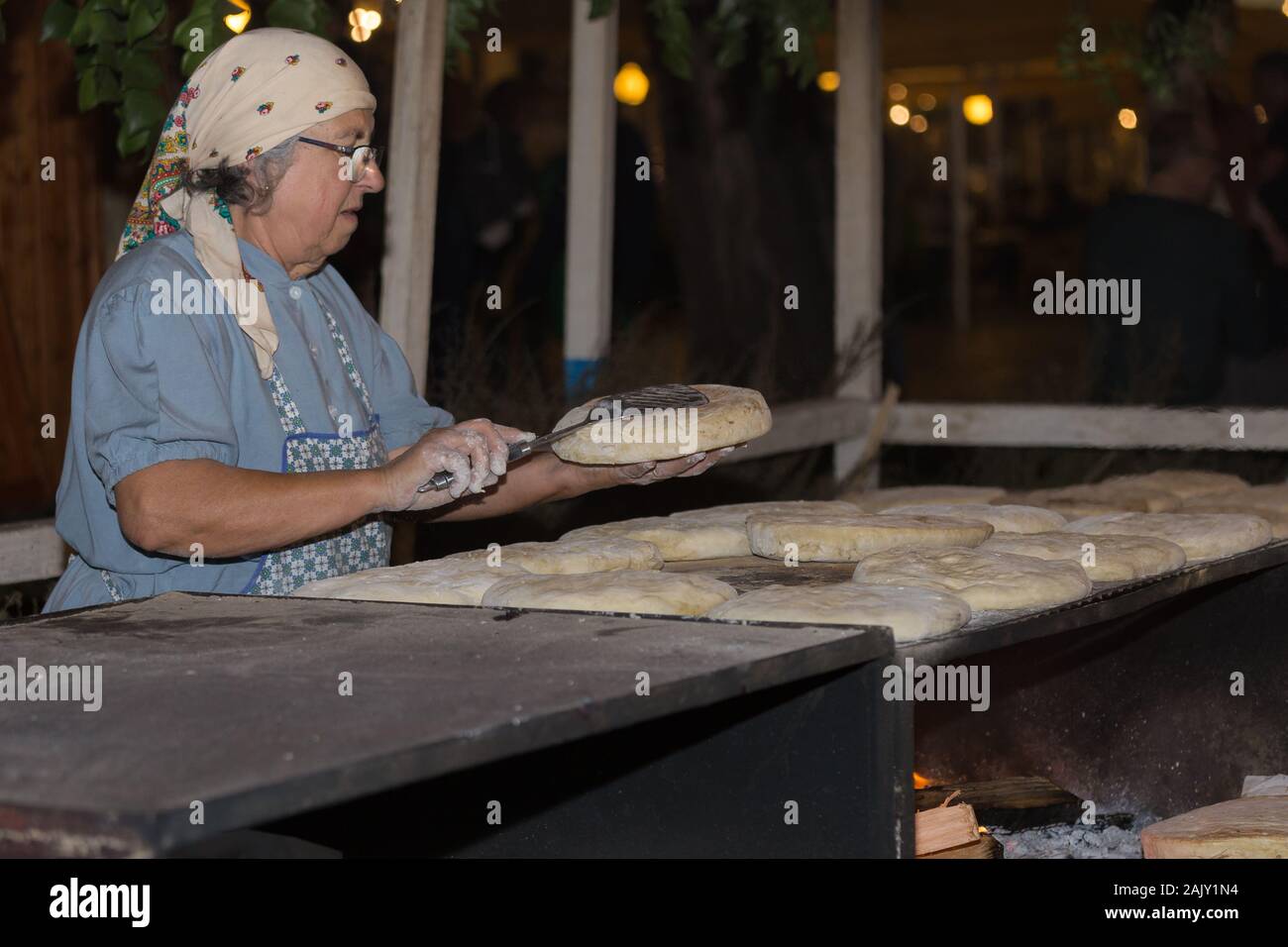 FUNCHAL, PORTUGAL - DECEMBER 2019: Woman making traditional "Bolo do ...