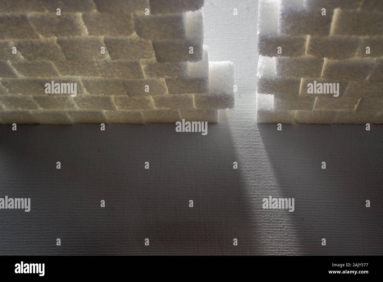 light shining through gap in a wall made out of sugar cubes ...
