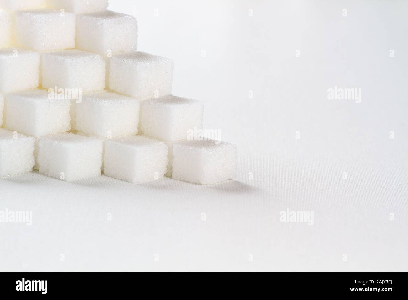 high key closeup of a pyramid of sugar cubes arranged in a cube pattern ...