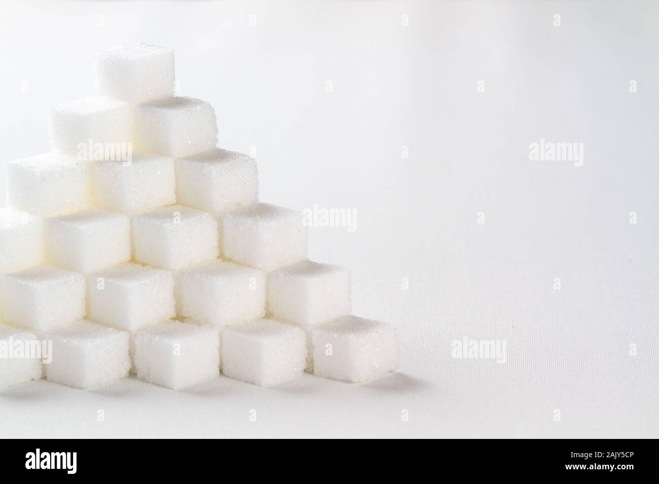 high key closeup of a pyramid of sugar cubes arranged in a cube pattern ...