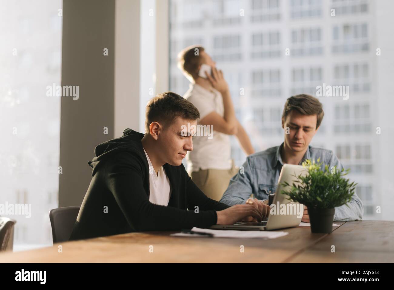 Two young adult startupers discussing project together at the table with laptop Stock Photo - Alamy