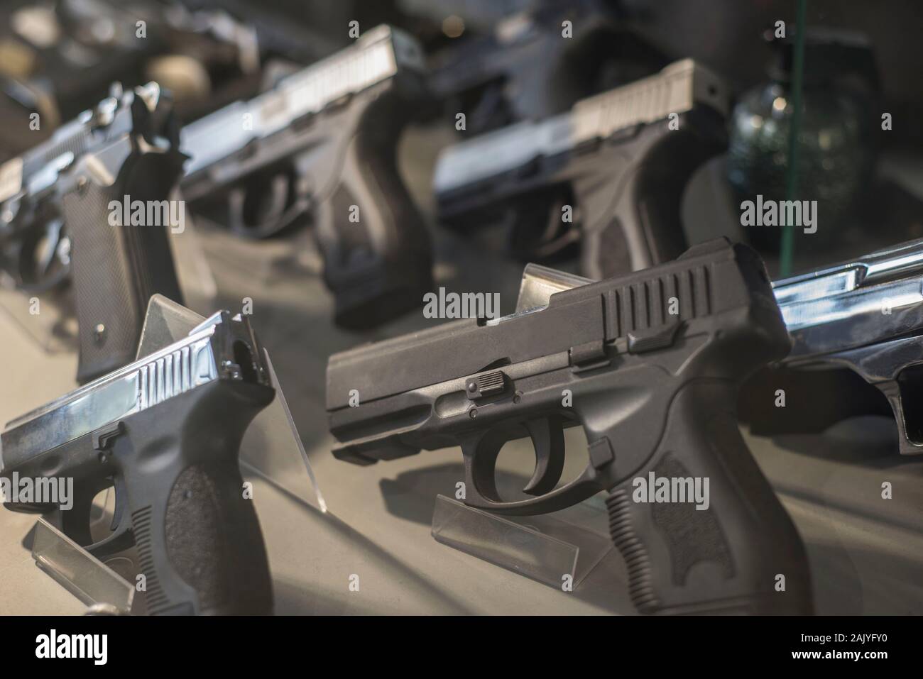 Black pistols behind the glass of a weapon store counter. Unusual view ...
