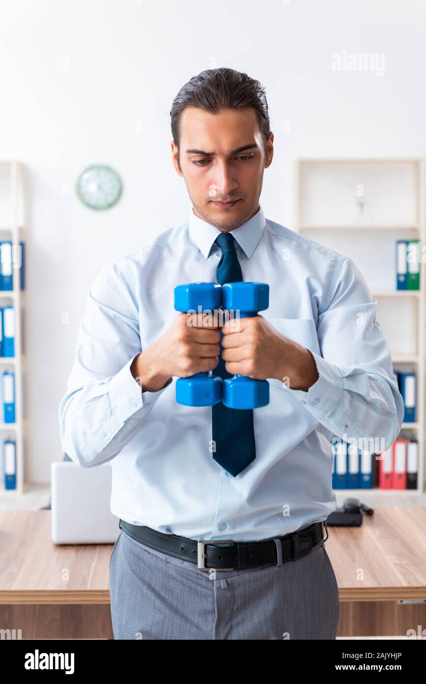 The young handsome employee doing sport exercises at workplace Stock ...