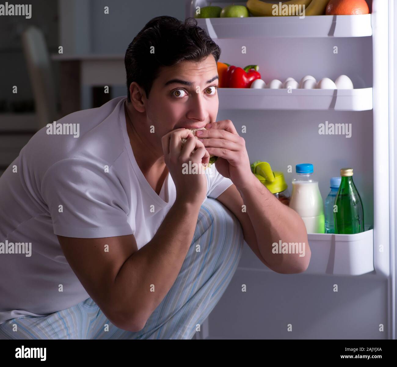 The man at the fridge eating at night Stock Photo - Alamy
