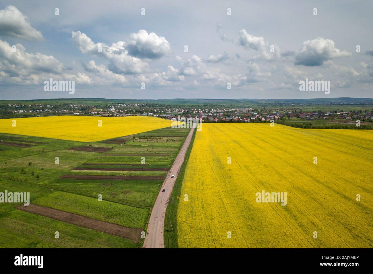 Aerial view of ground road with moving cars in green fields with ...