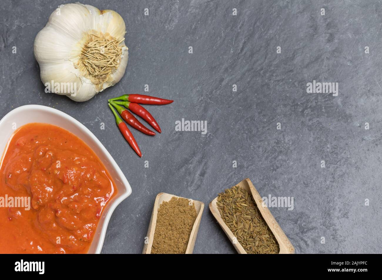 Top view of the Harissa sauce and ingredients on the dark slate stone ...