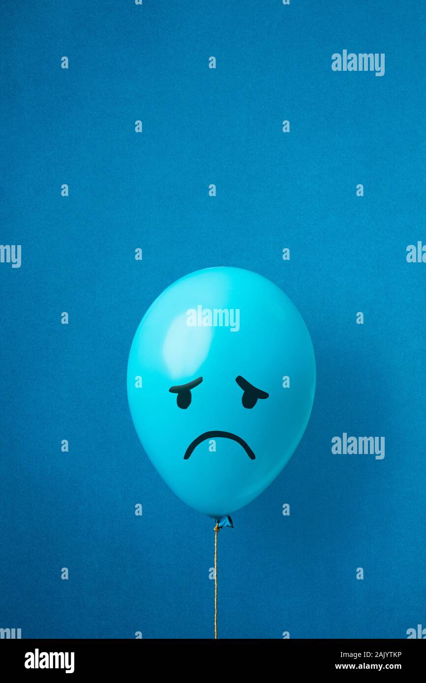 Stock photo of a blue balloon on a blue background with a sad face ...