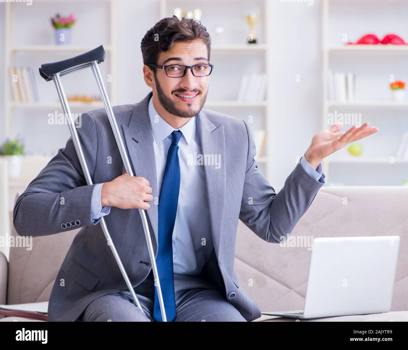 The businessman with crutches and broken leg at home working Stock ...