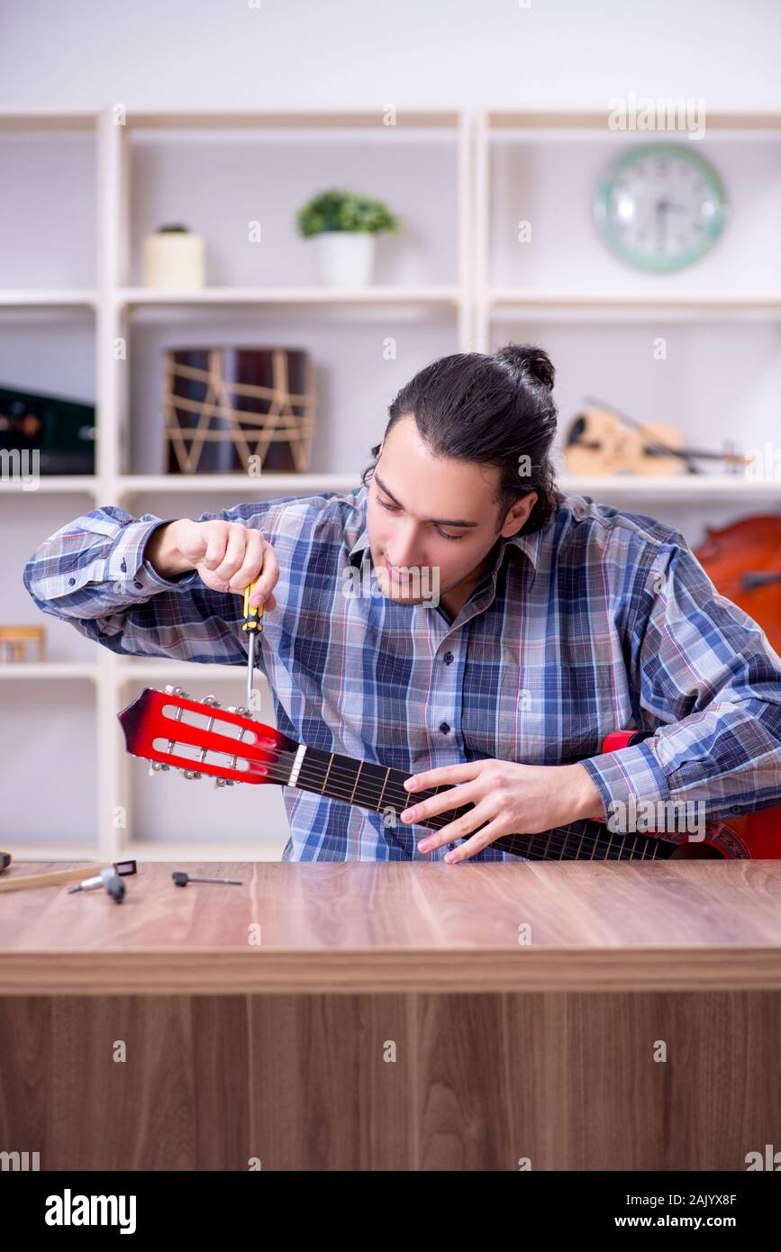The young handsome repairman repairing guitar Stock Photo - Alamy