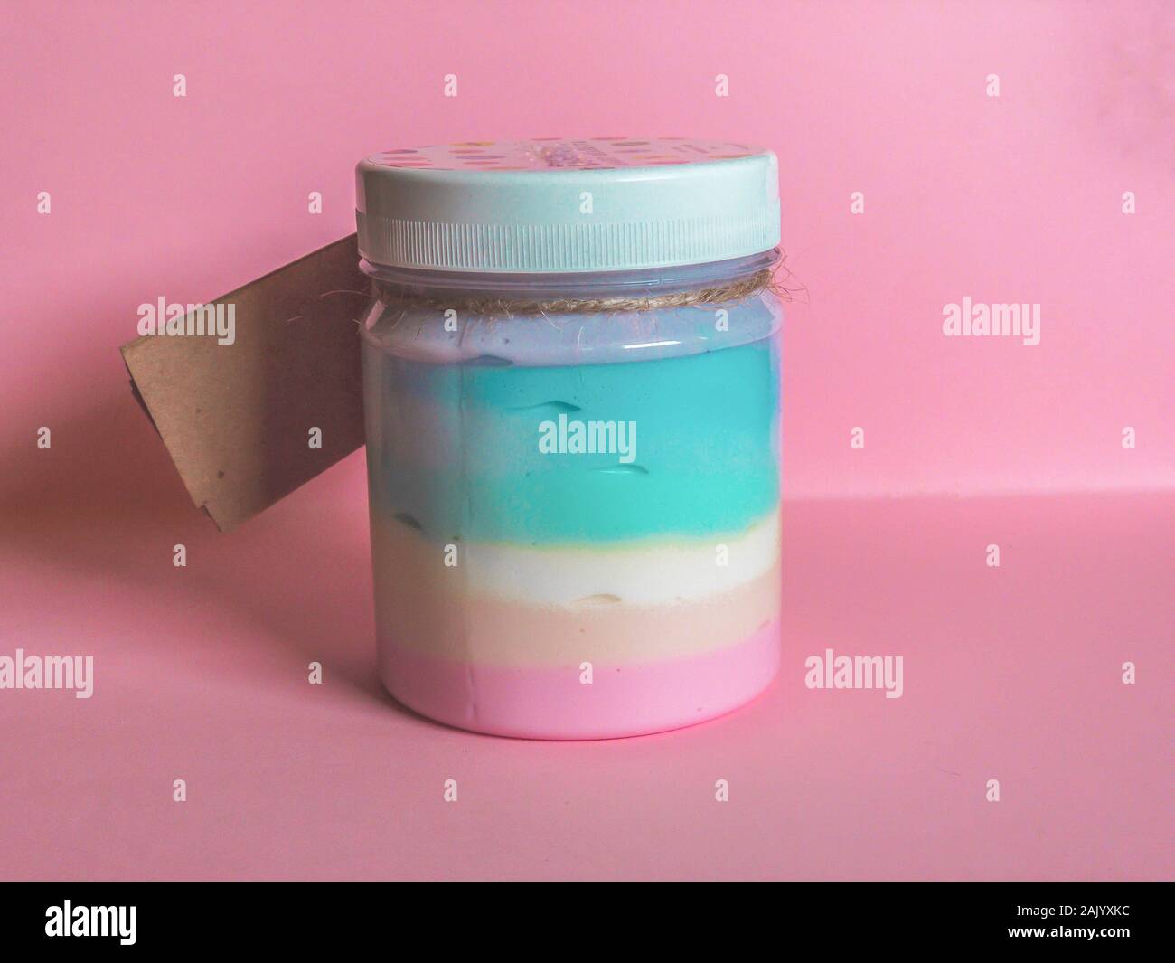 Bottle with body lotion of rainbow colors on a pink background. Body ...