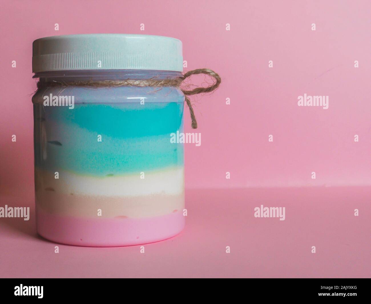 Bottle with body lotion of rainbow colors on a pink background. Body ...