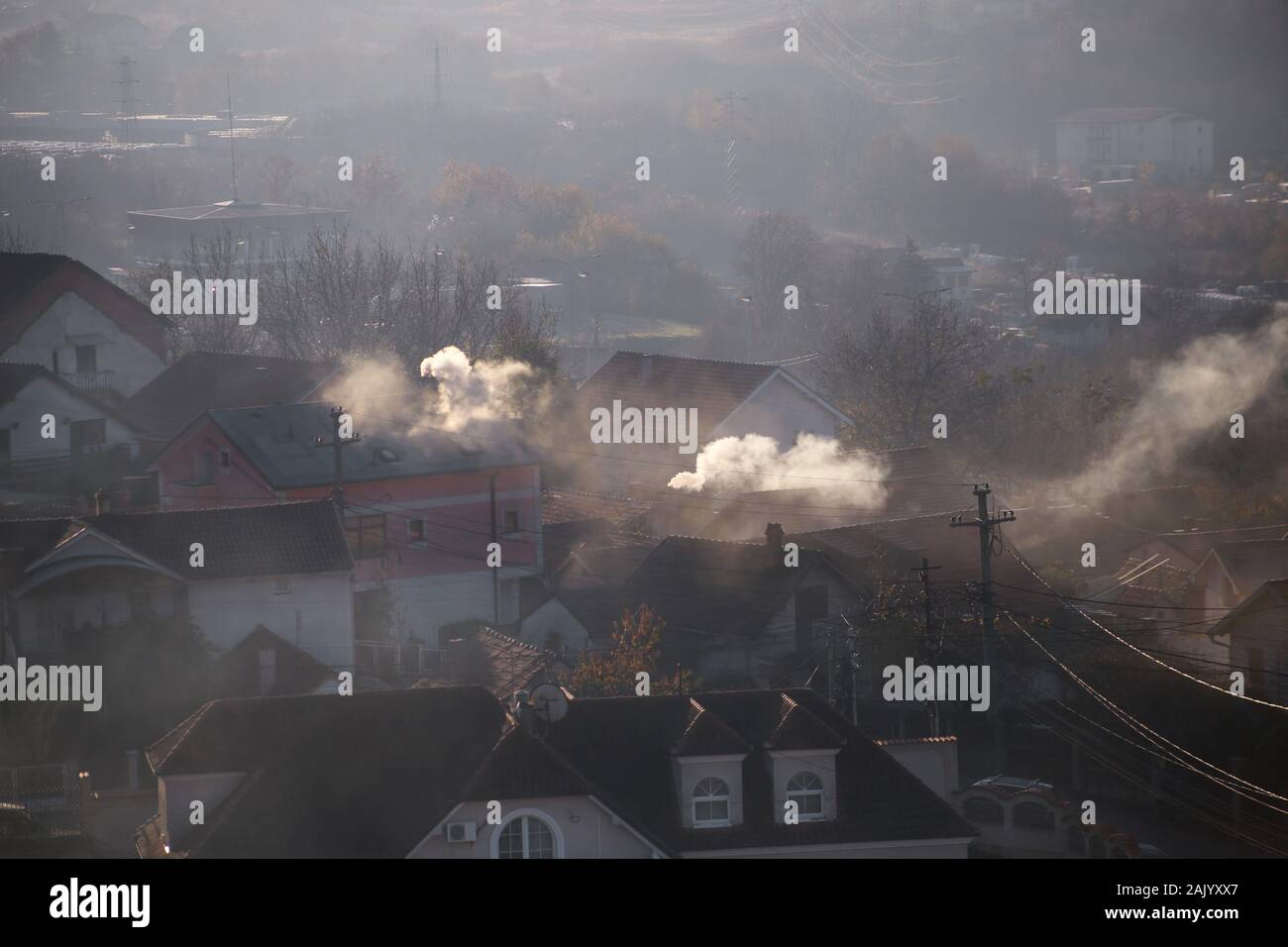 Smoking chimneys at roofs of houses emits smoke, smog at sunrise ...