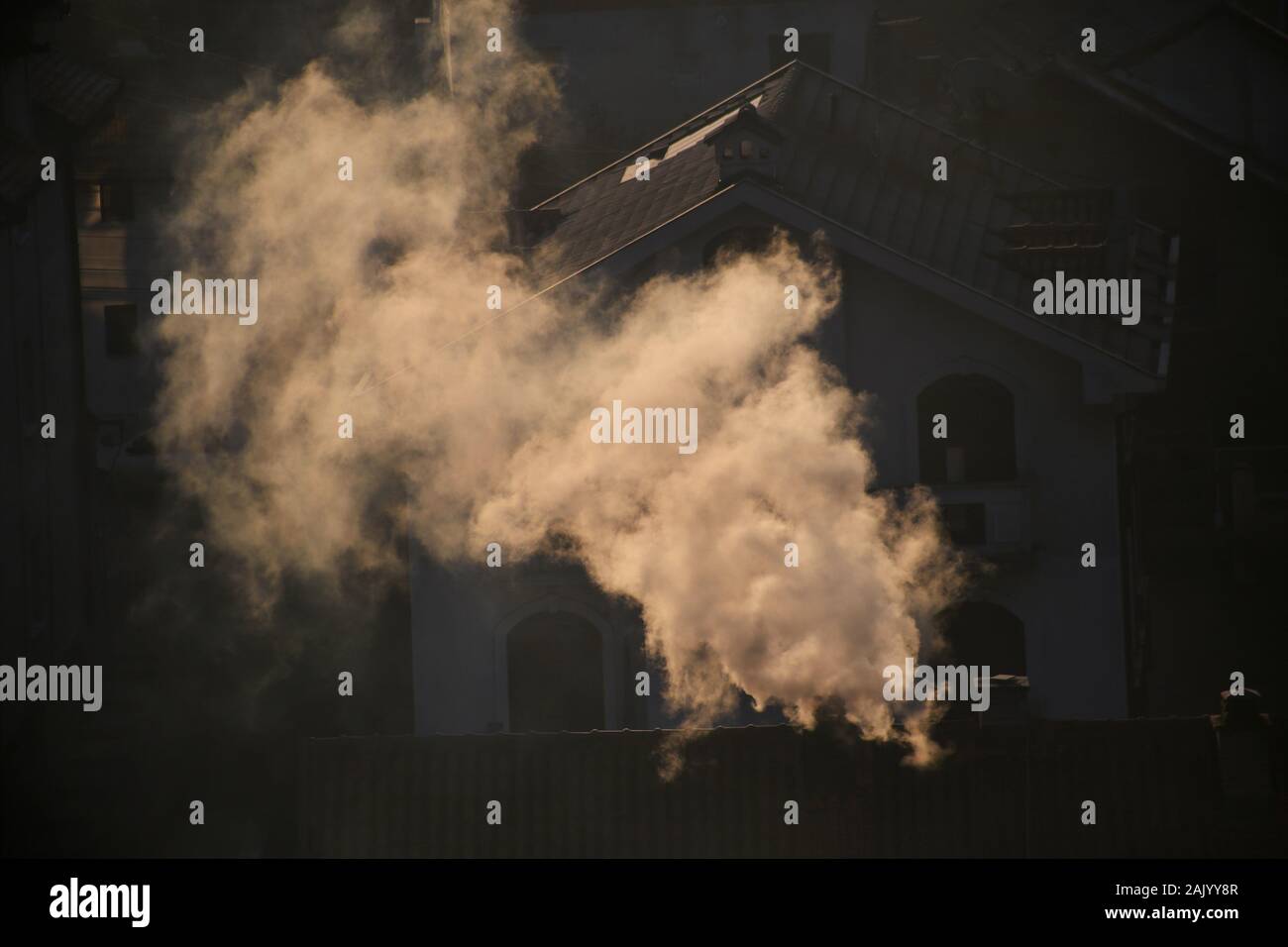 Smoking chimneys at roofs of houses emits smoke, smog at sunrise ...