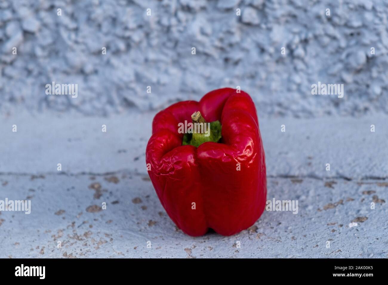 a red pepper in front of a wall Stock Photo - Alamy