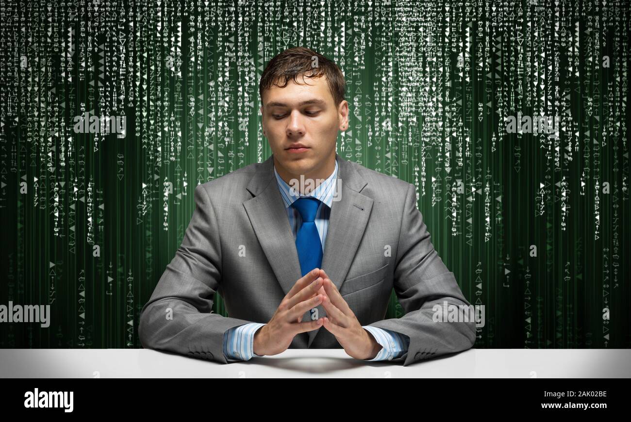 Young serious man folded hands and sitting at desk Stock Photo - Alamy