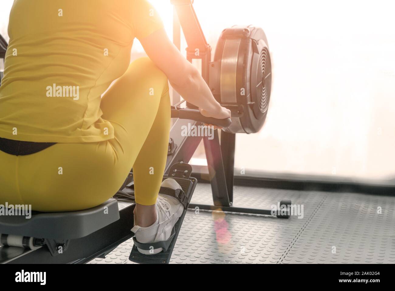 Back view of woman uses a rowing machine Stock Photo - Alamy