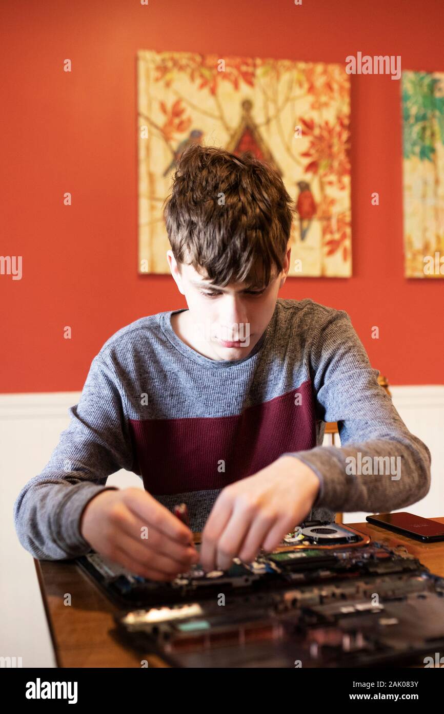A sixteen-year-old teenage boy takes apart an old laptop computer Stock ...