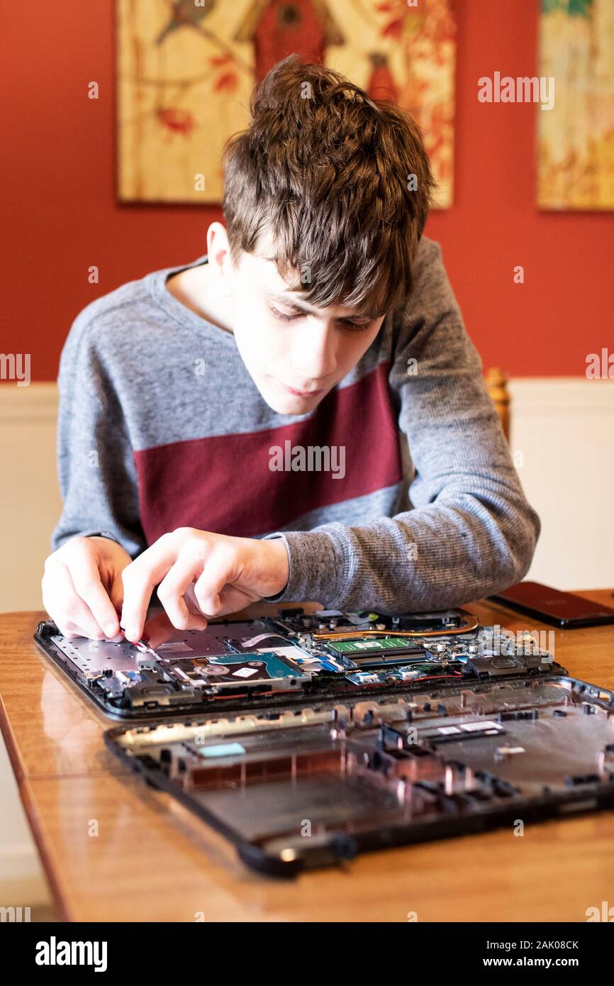 A sixteen-year-old teenage boy takes apart an old laptop computer Stock ...