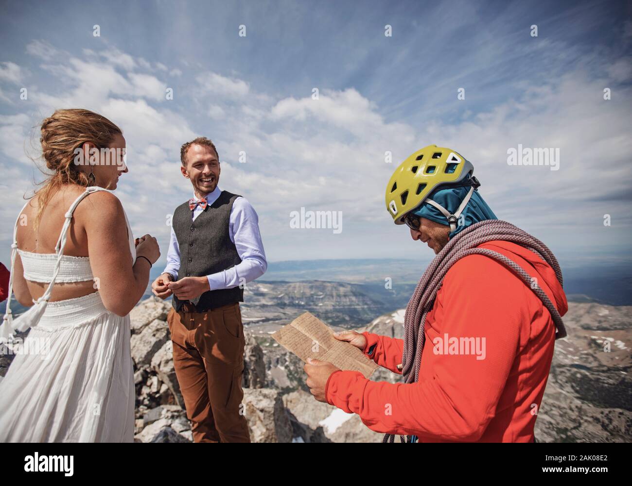 Climbing guide with helmet reads vows during mountaintop wedding Stock ...