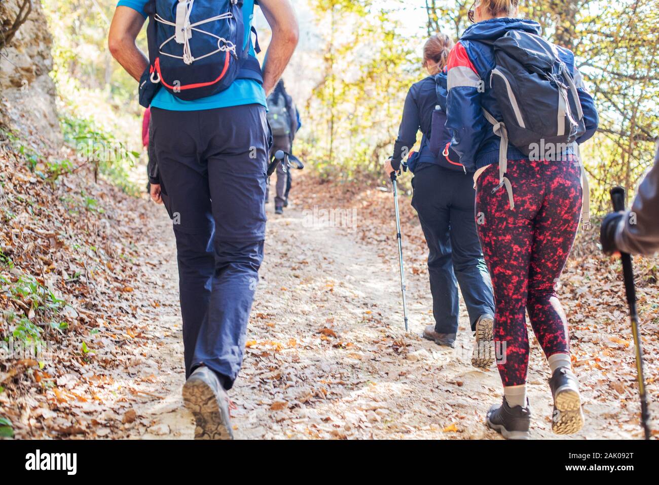 Group of active people walking on a rural road in an autumn day ...