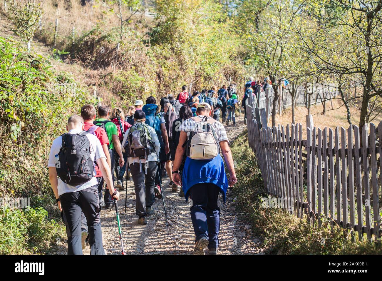 Group of active people walking on a rural road in an autumn day ...