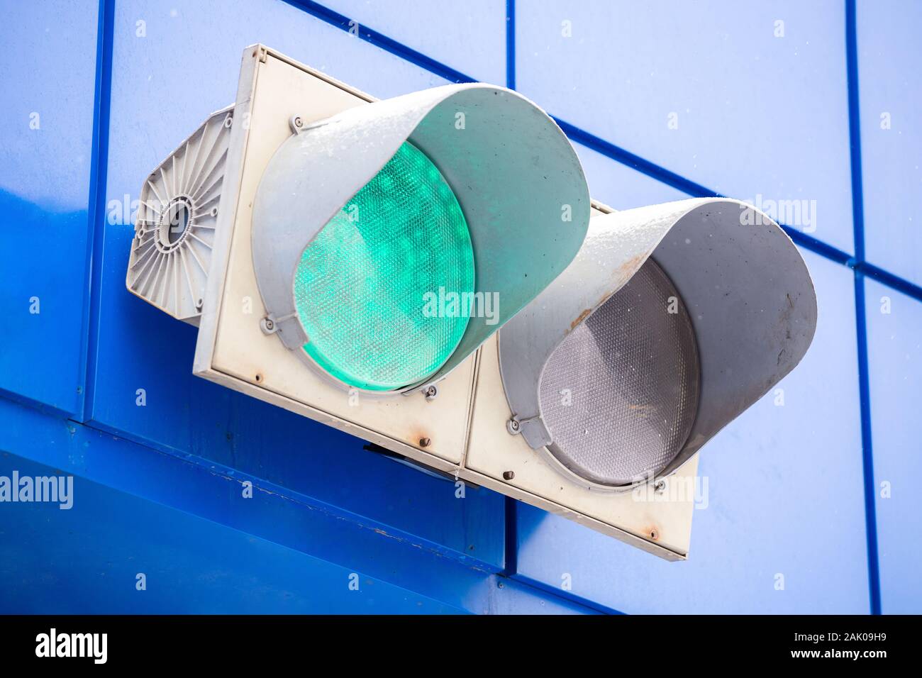 Illuminated green traffic signal light on classic blue wall of a garage ...