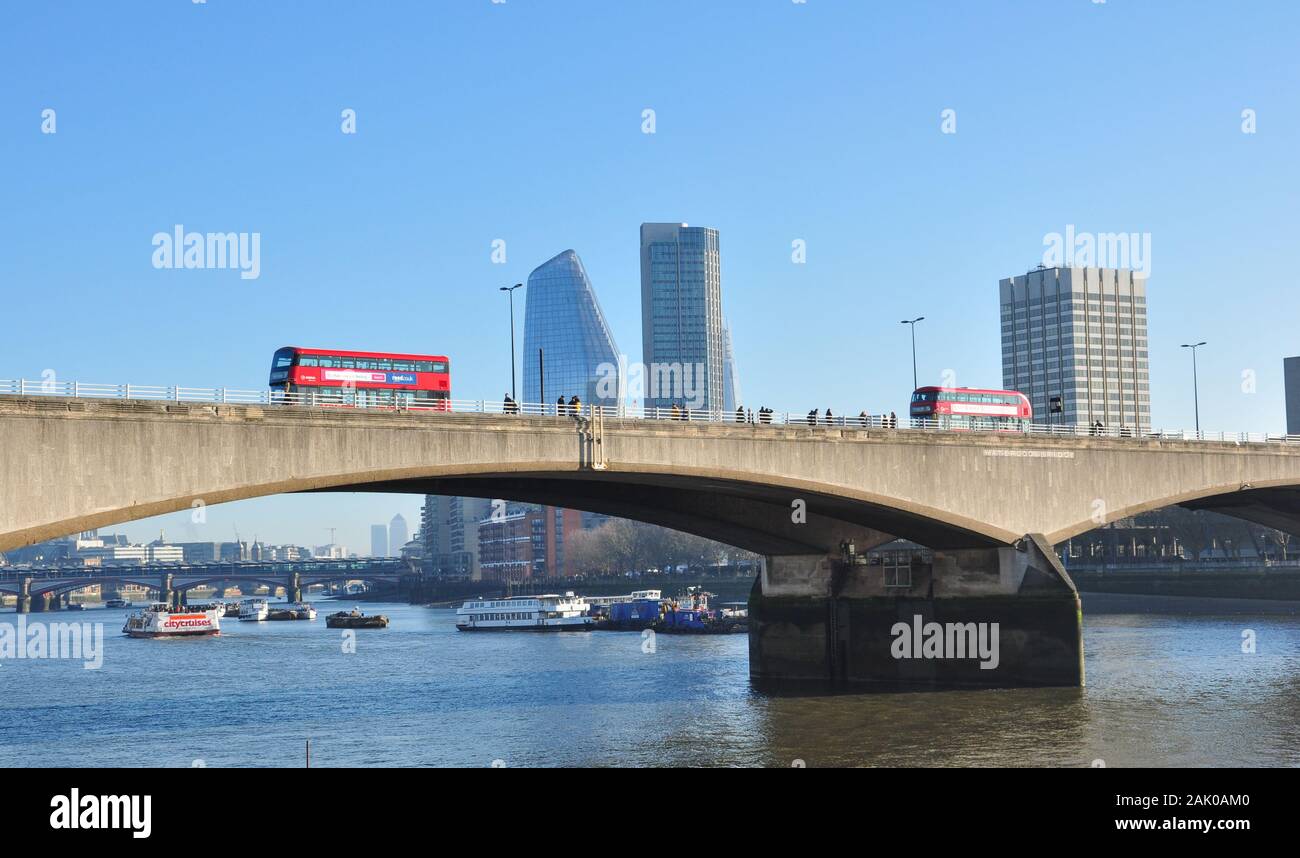 Buses on Waterloo Bridge, boats on the River Thames and high rise ...