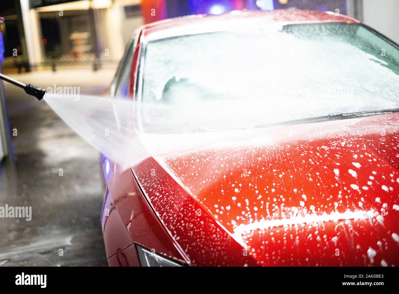 Person washing a red car with high pressure water in a car wash. Car ...