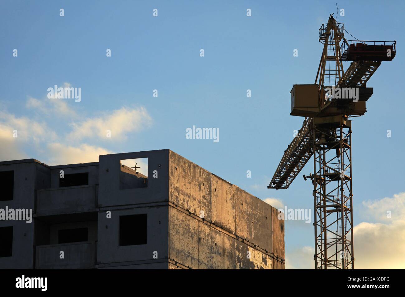 An old construction crane and unfinished panel multifamily house at the ...