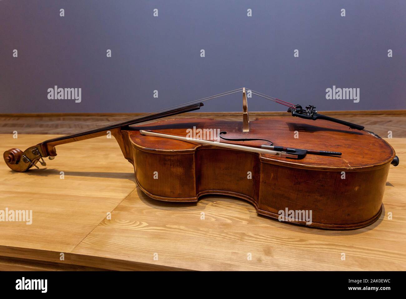 An old broken double bass lying on a wooden table on the background of ...